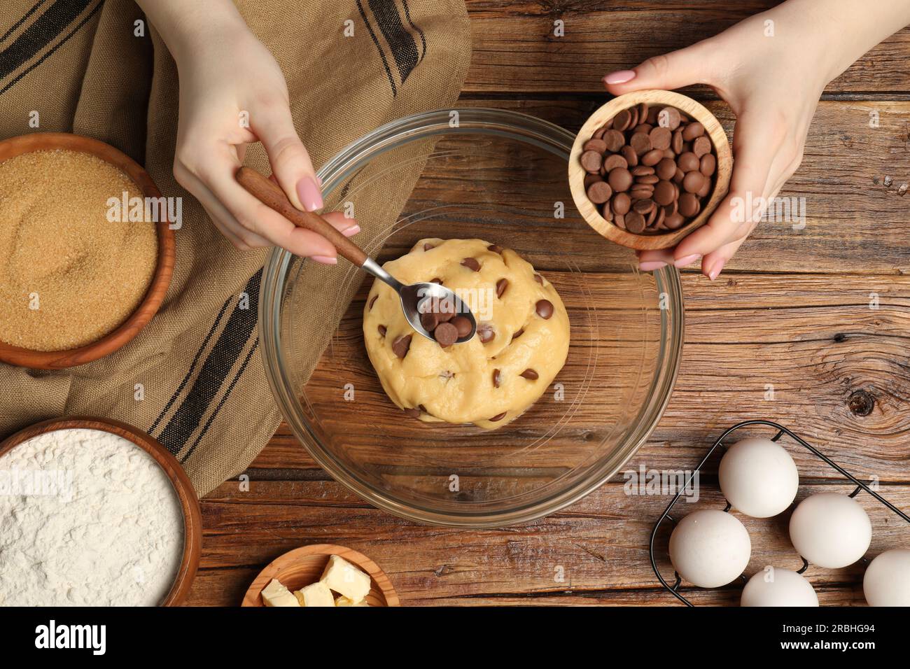Cooking sweet cookies. Woman adding chocolate chips to dough at wooden ...