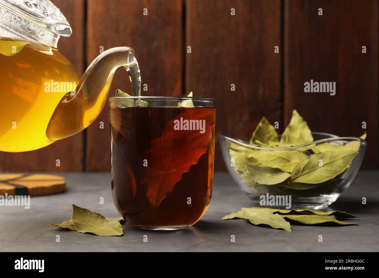 Pouring freshly brewed tea with bay leaves into cup on grey table Stock ...