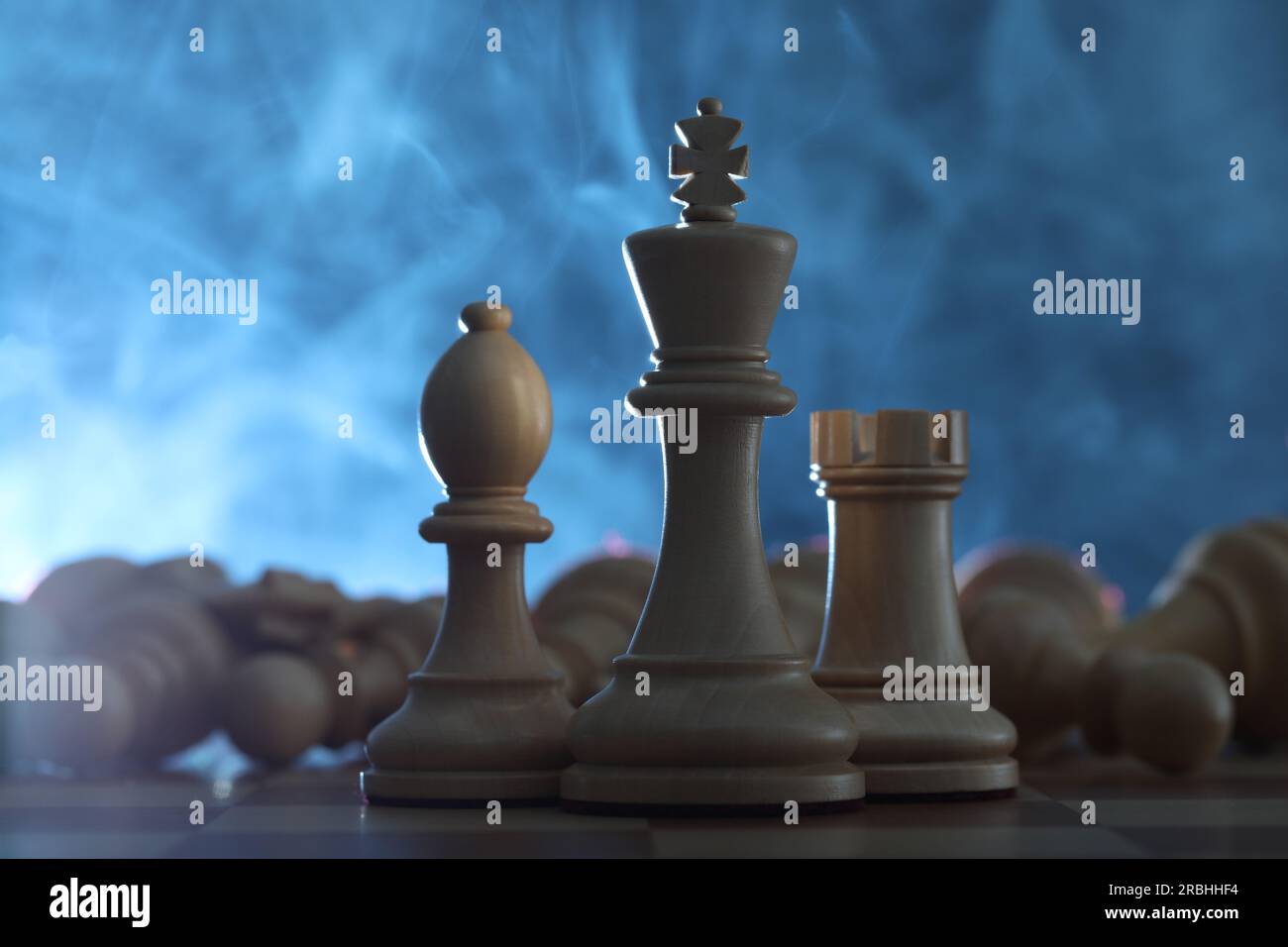 Wooden king, rook and bishop in front of fallen chess pieces on ...