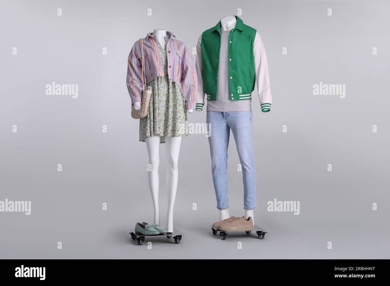 Male and female mannequins dressed in stylish outfits on grey ...