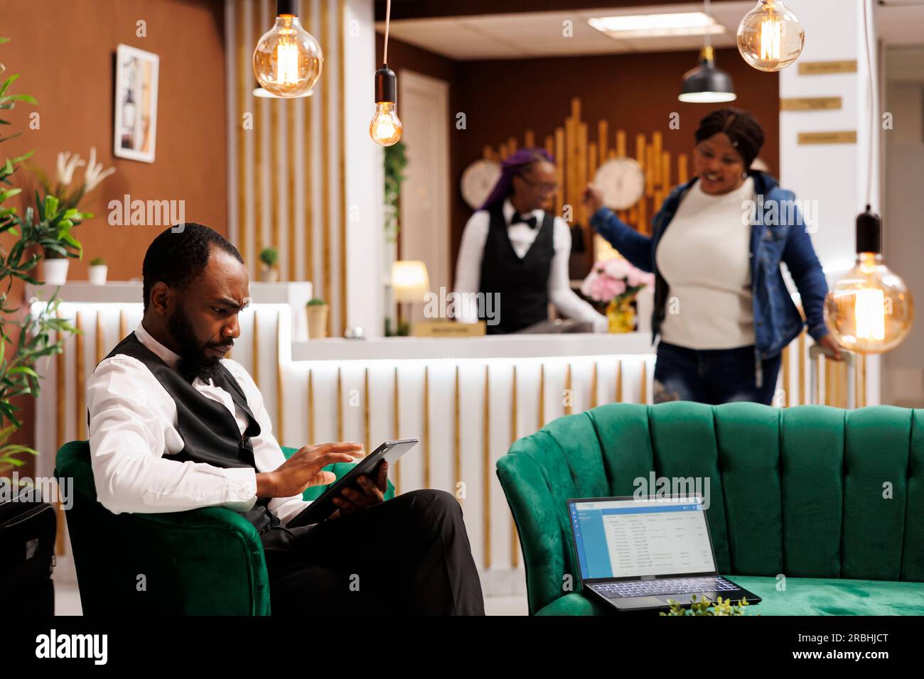 African American male hotel manager wearing uniform sitting in lobby ...