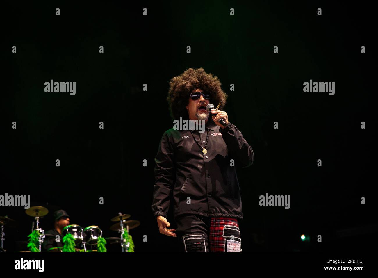 B-Real of Cypress Hill performs on stage sporting sunglasses, a large ...