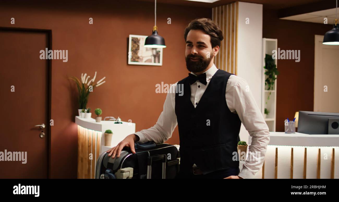 Panning shot of happy smiling professional bellhop employee in formal ...