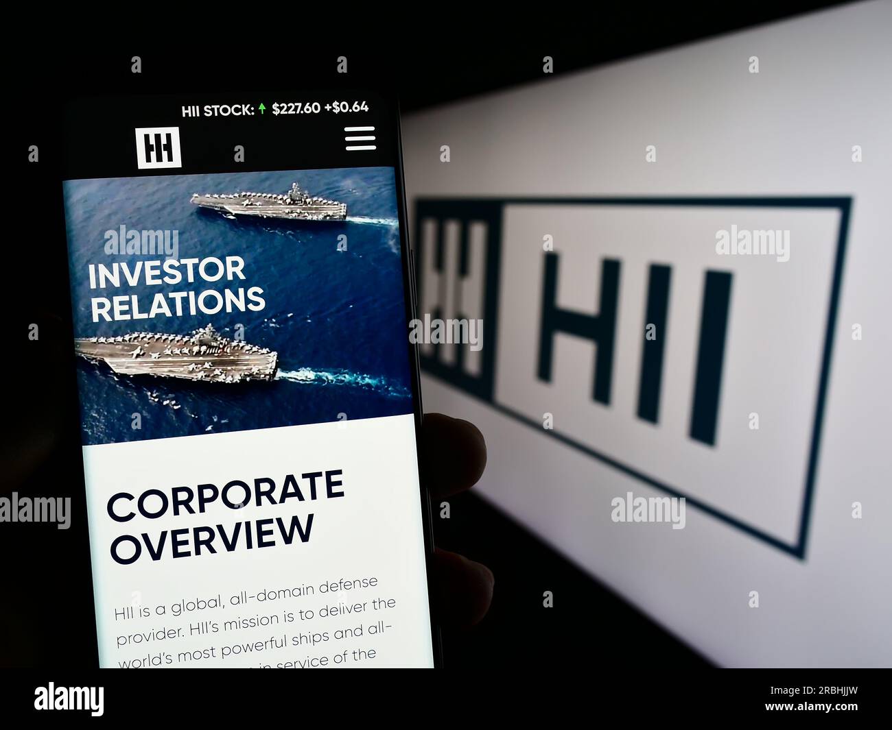 Person holding cellphone with web page of US shipbuilding company HII ...