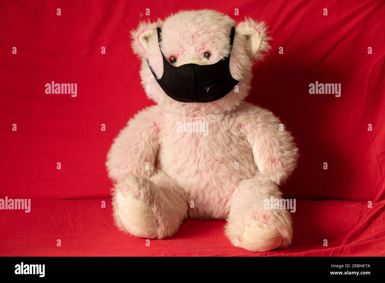 children's soft plush toys in medical mask lie on the red sofa ...
