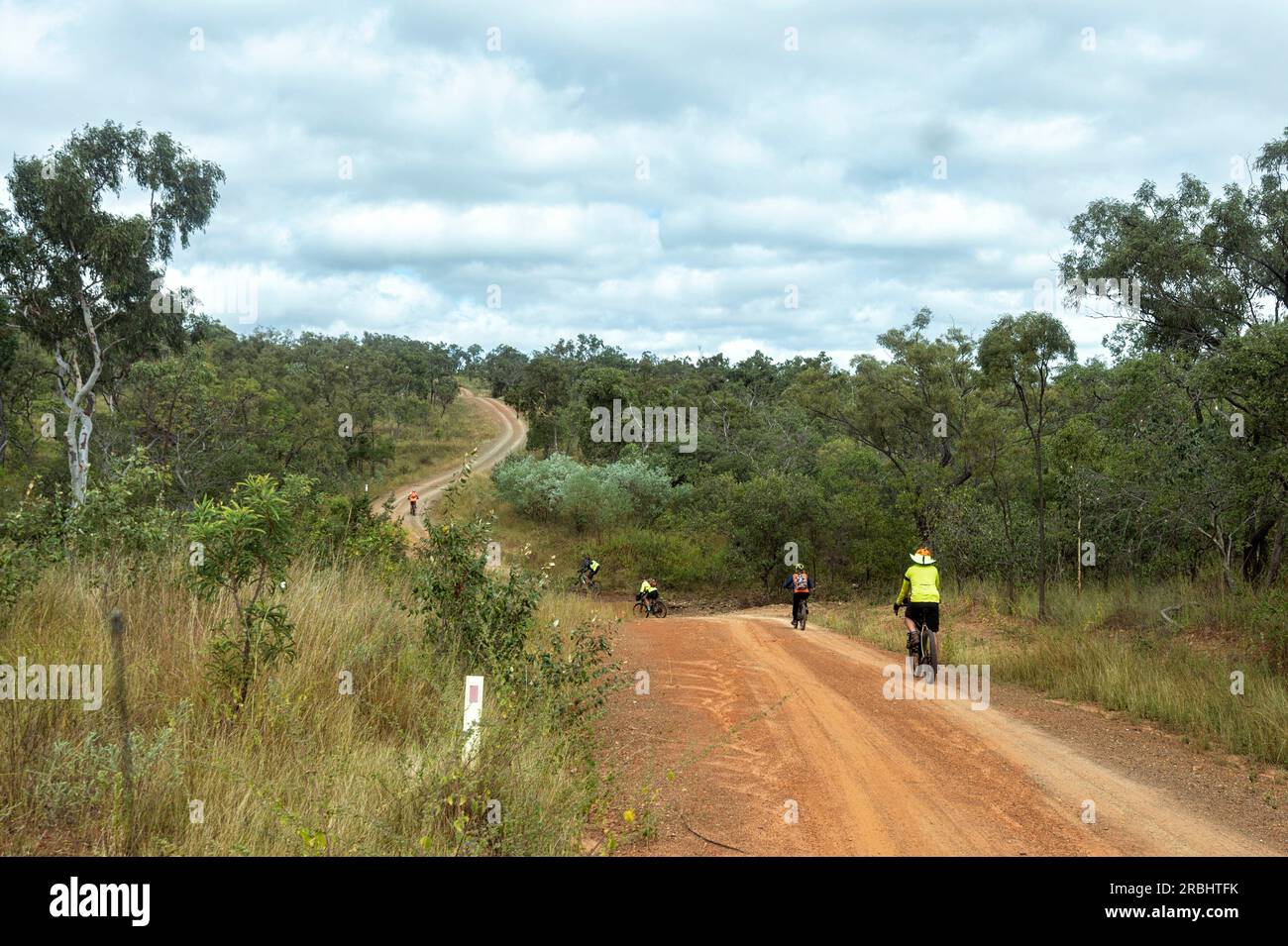Cyclists riding on a remote rural hilly dirt road near Irvinebank ...