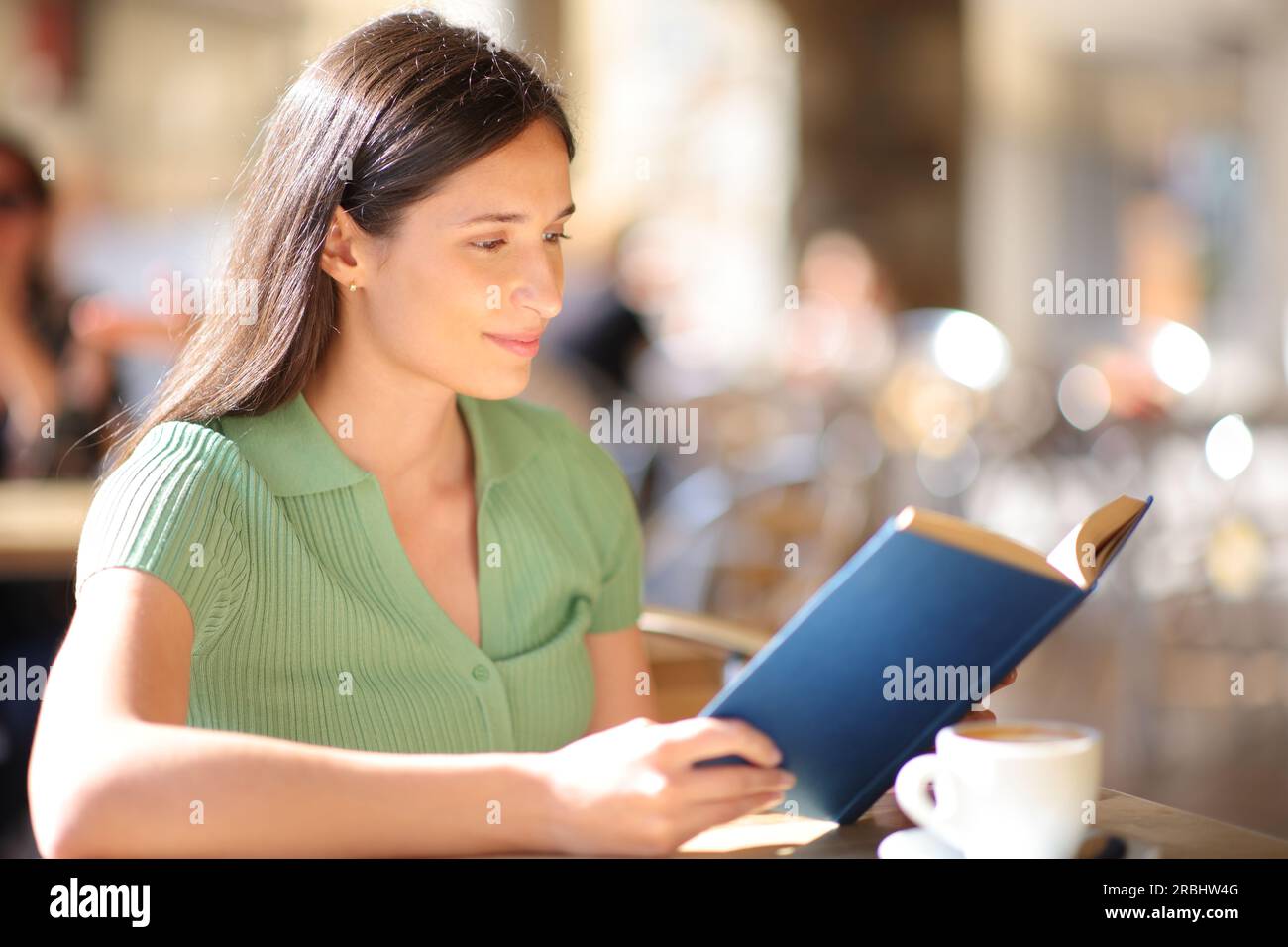 Woman reading a paper book in a terrace of a coffee shop Stock Photo ...