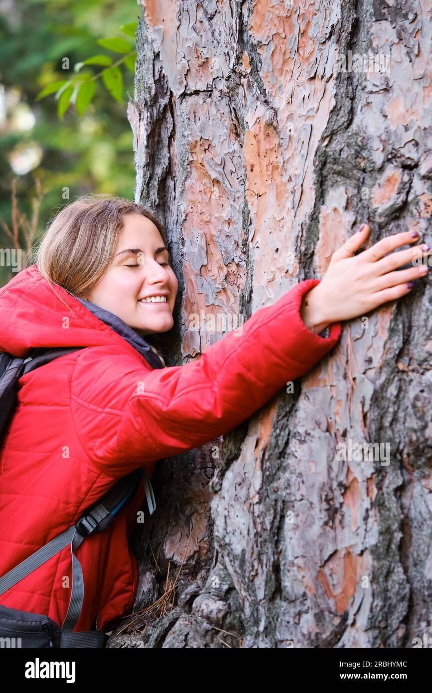 Smiling environmentalist hugging a tree in the forest Stock Photo - Alamy
