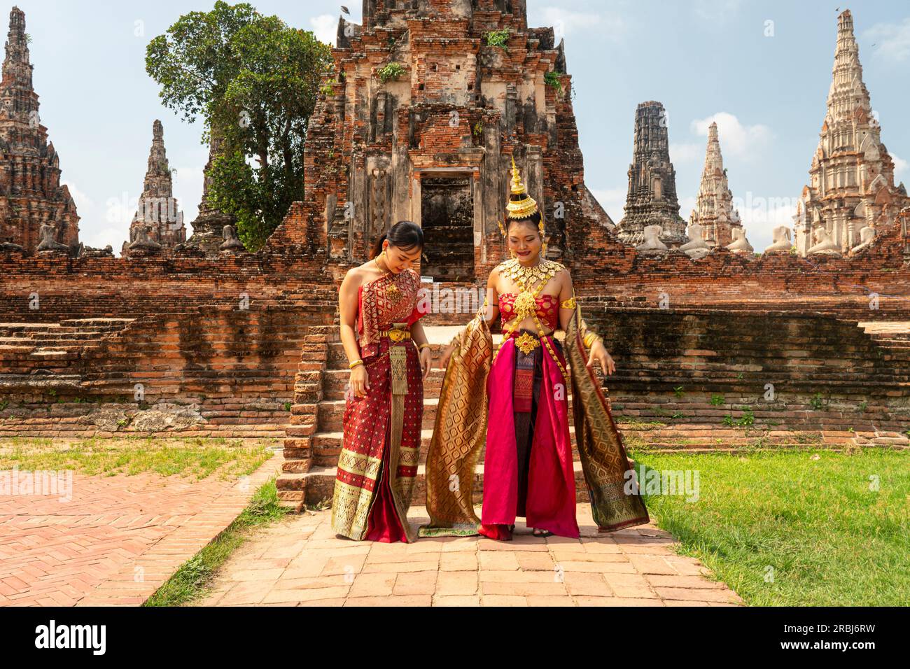 Thai girls in traditional Thai costume with red umbrella in Thai temple, identity culture of ...