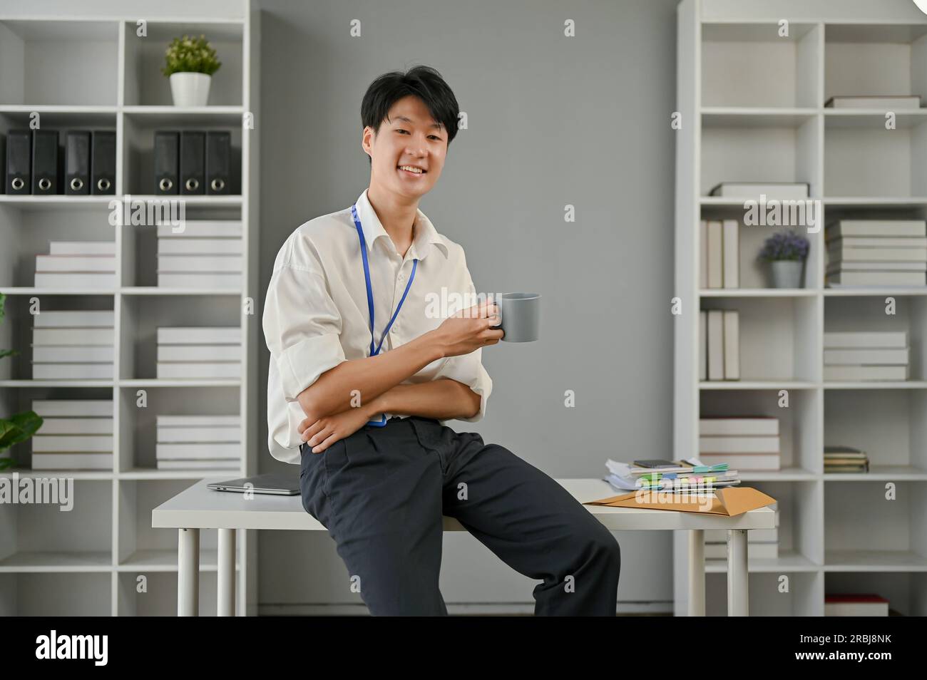 A handsome and happy young Asian businessman or male banker is sitting ...