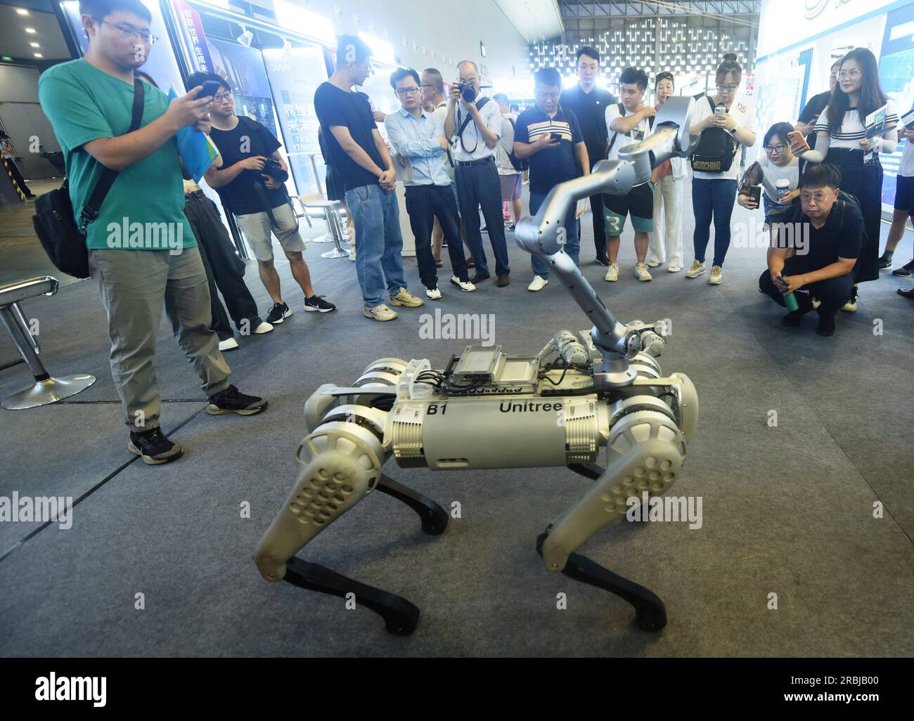 Visitors check out the quadruped robot exhibited by Unitree Robotics at ...