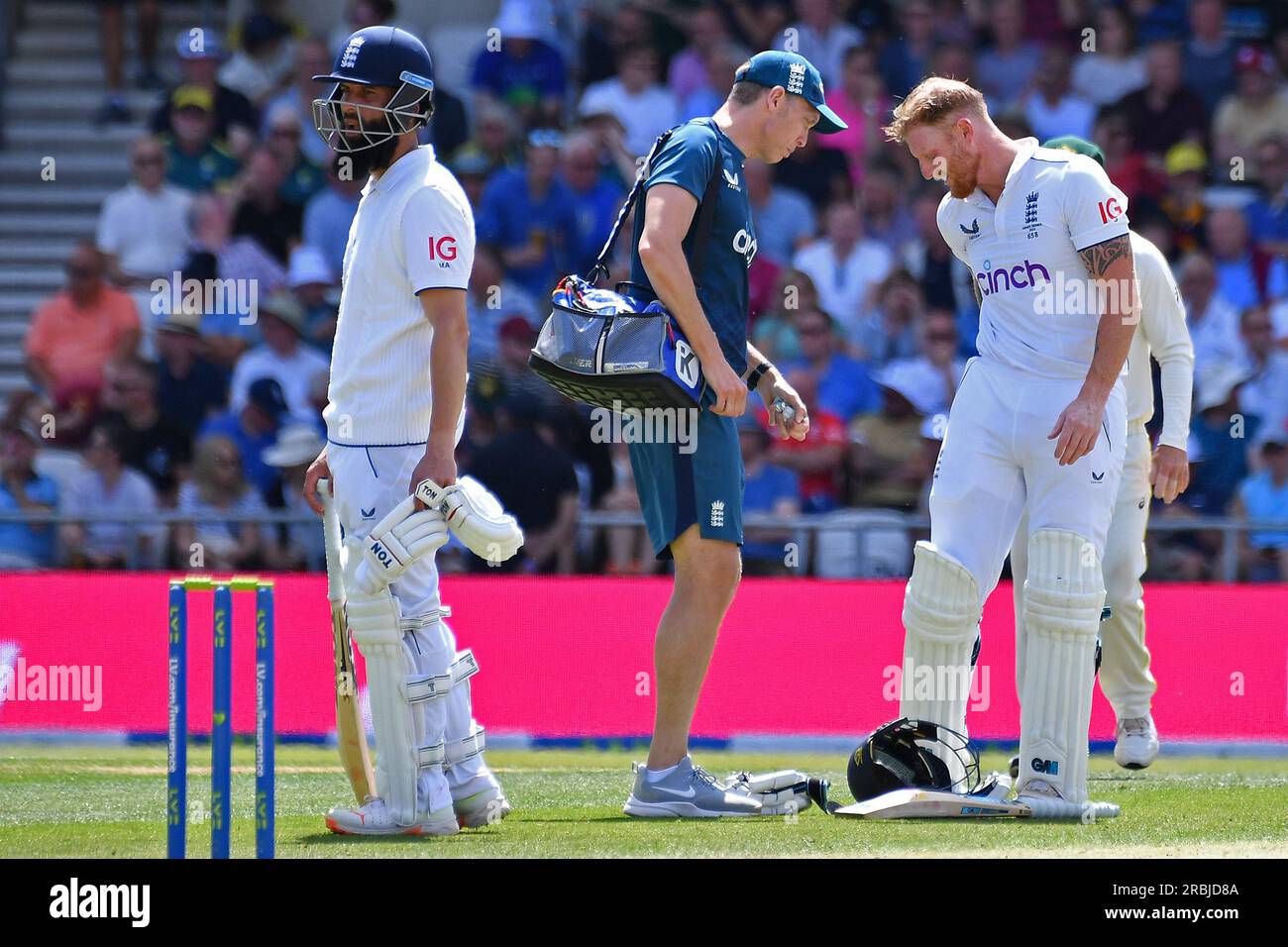 A member of team support staff, center, attends to England's captain ...