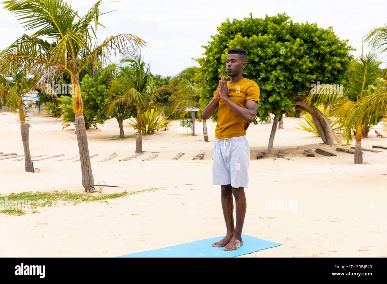 Biracial man with eyes closed practicing yoga meditation standing on ...