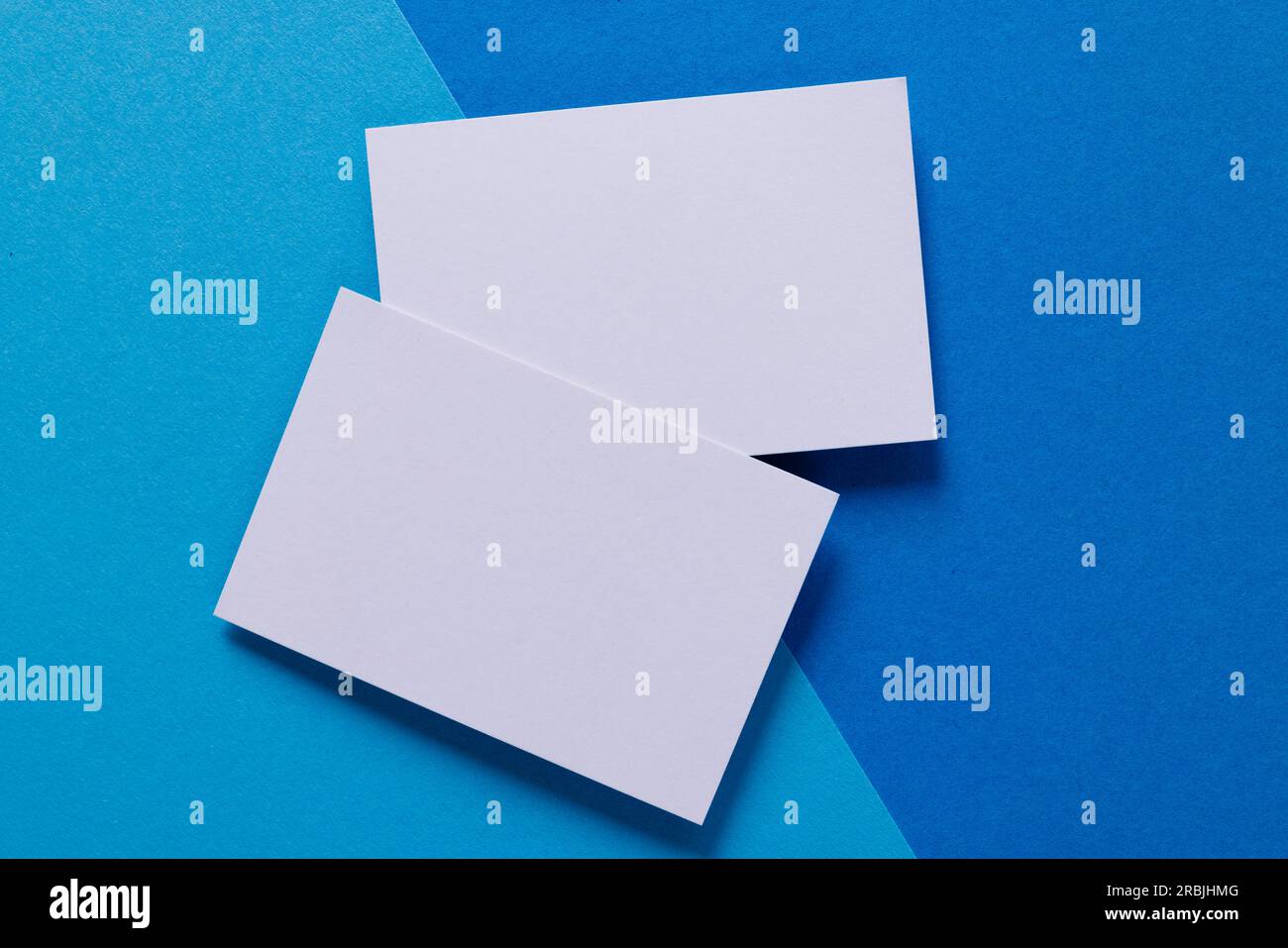 White business cards with copy space on light and dark blue background ...