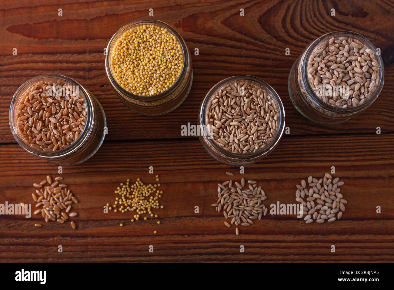 Cereal grains in glass jars on wooden background. Collection of ...