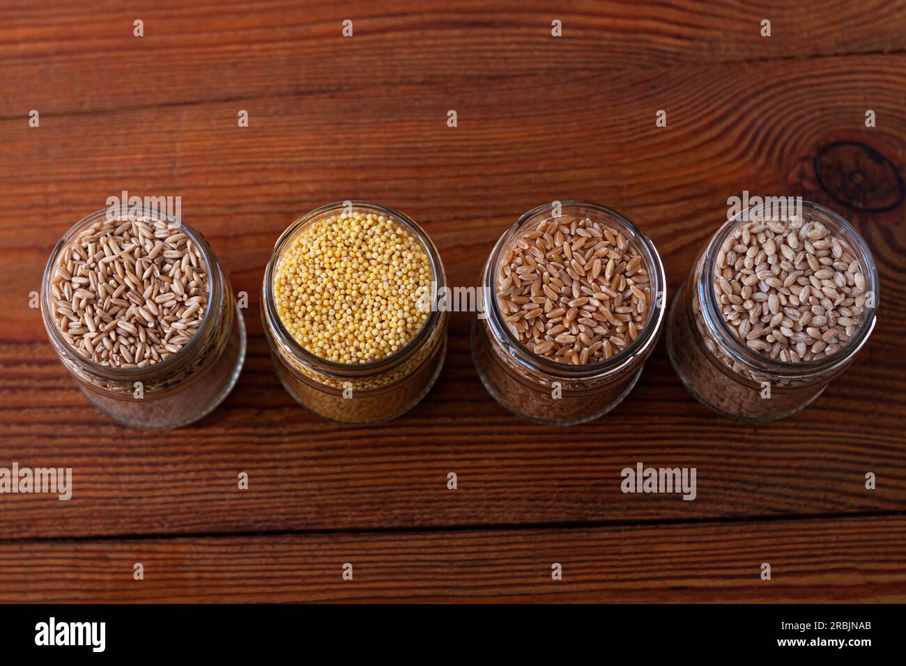 Cereal grains in glass jars on wooden background. Collection of ...