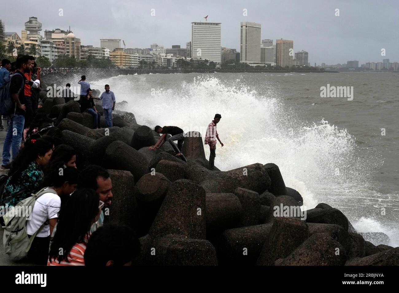 People stand on rocks by the Arabian Sea front in Mumbai, India ...