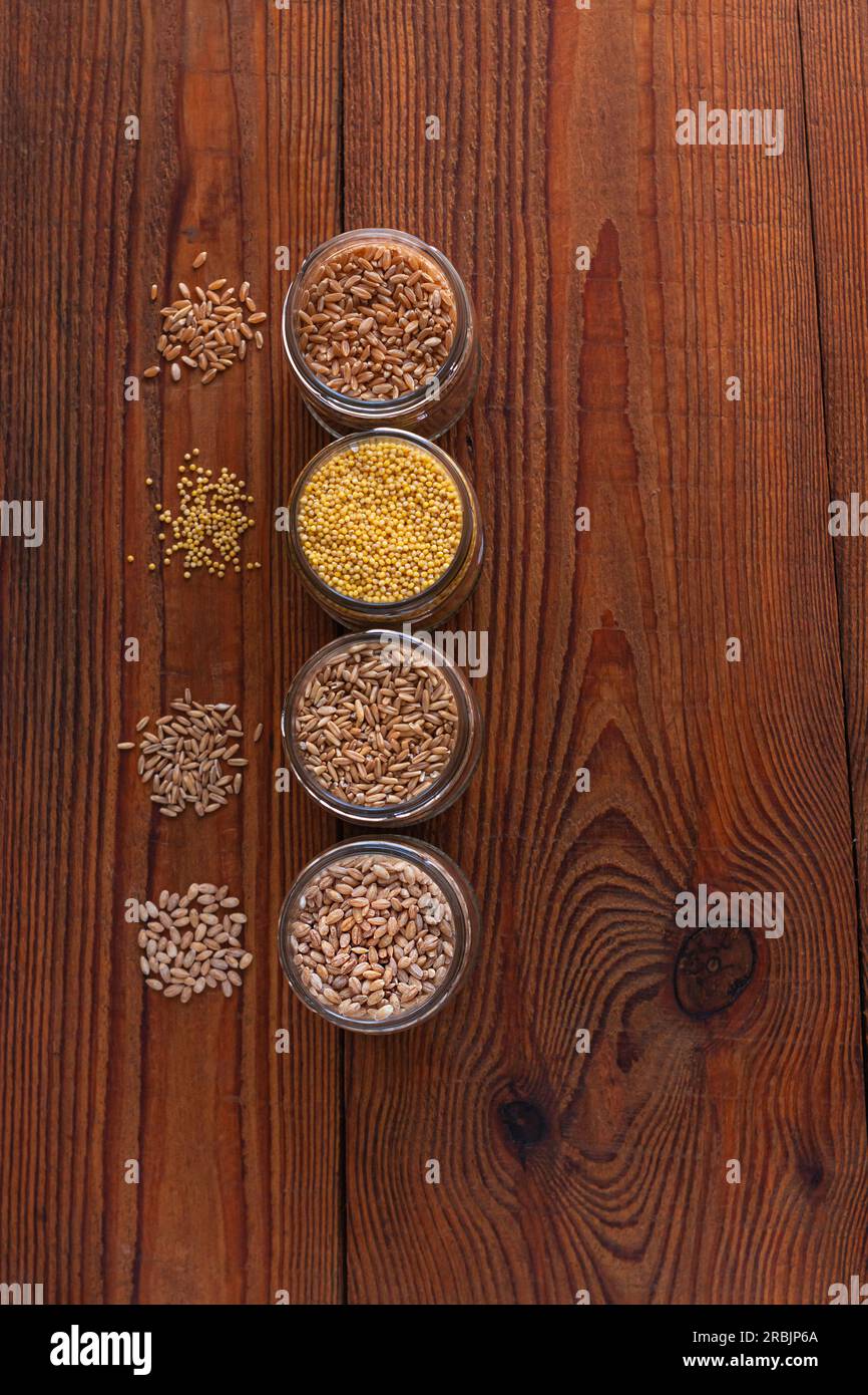 Cereal grains in glass jars on wooden background. Collection of ...