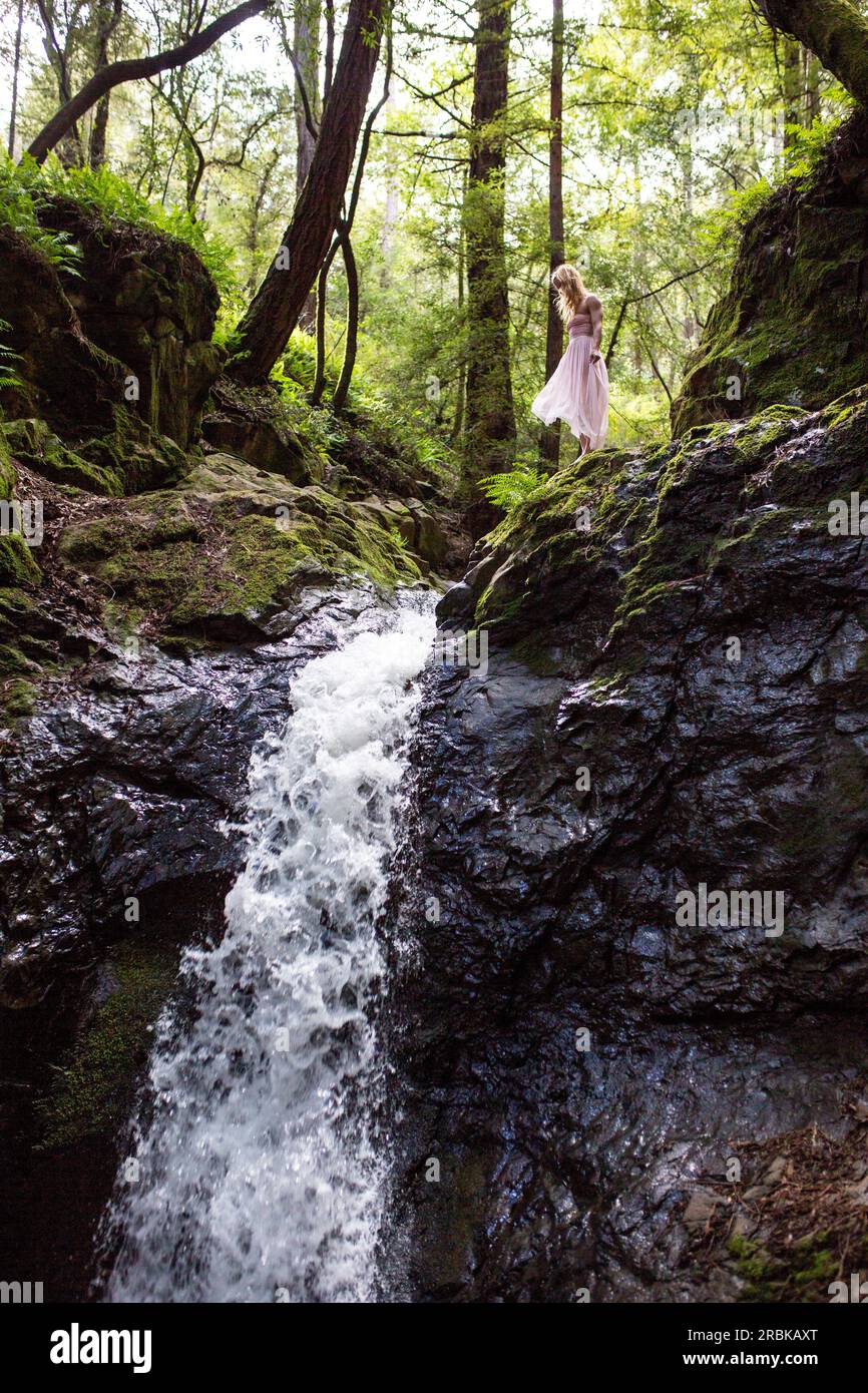 Woman looking over edge of waterfall Stock Photo - Alamy