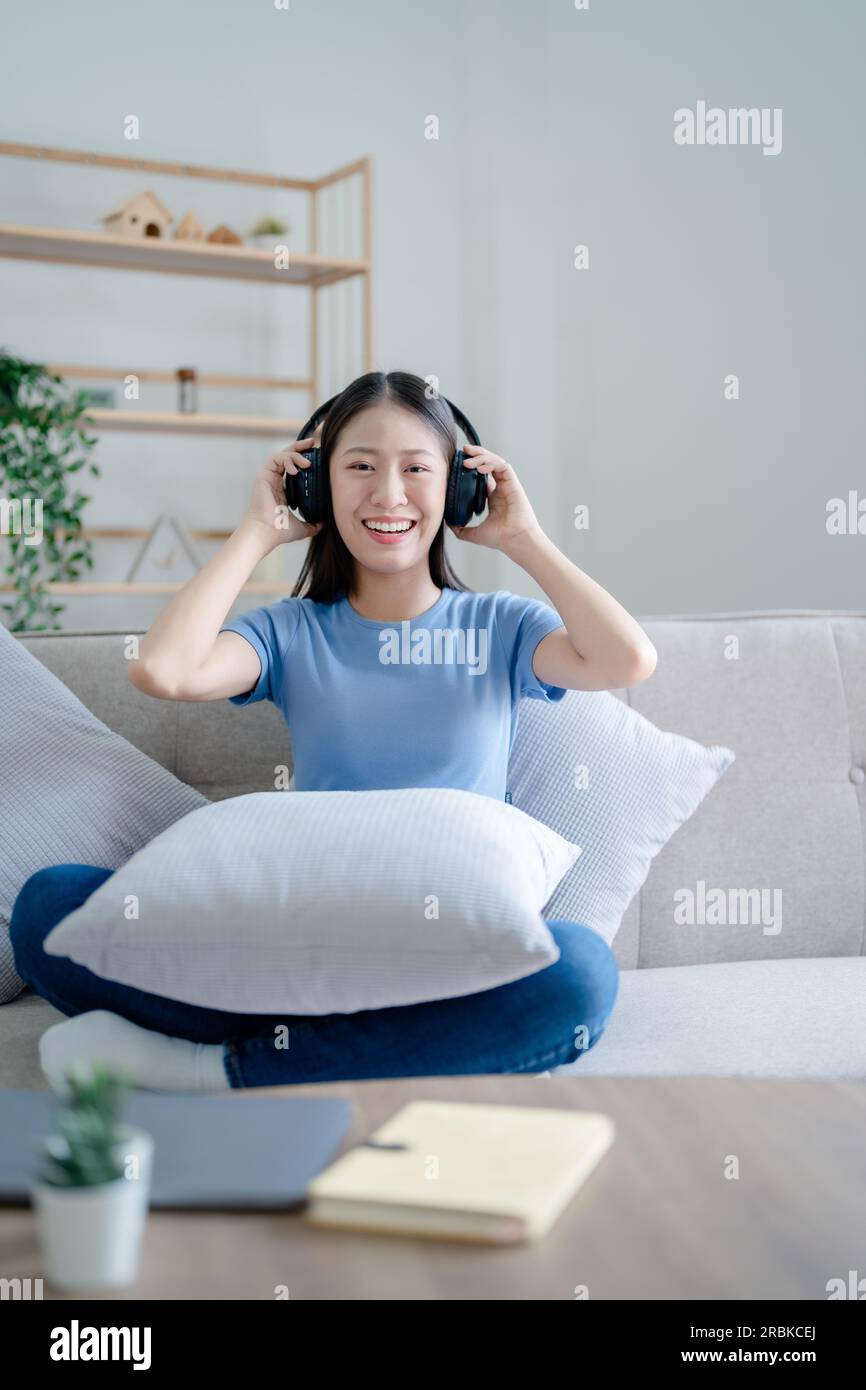 Peaceful girl in modern wireless headphones sit relax on comfortable ...