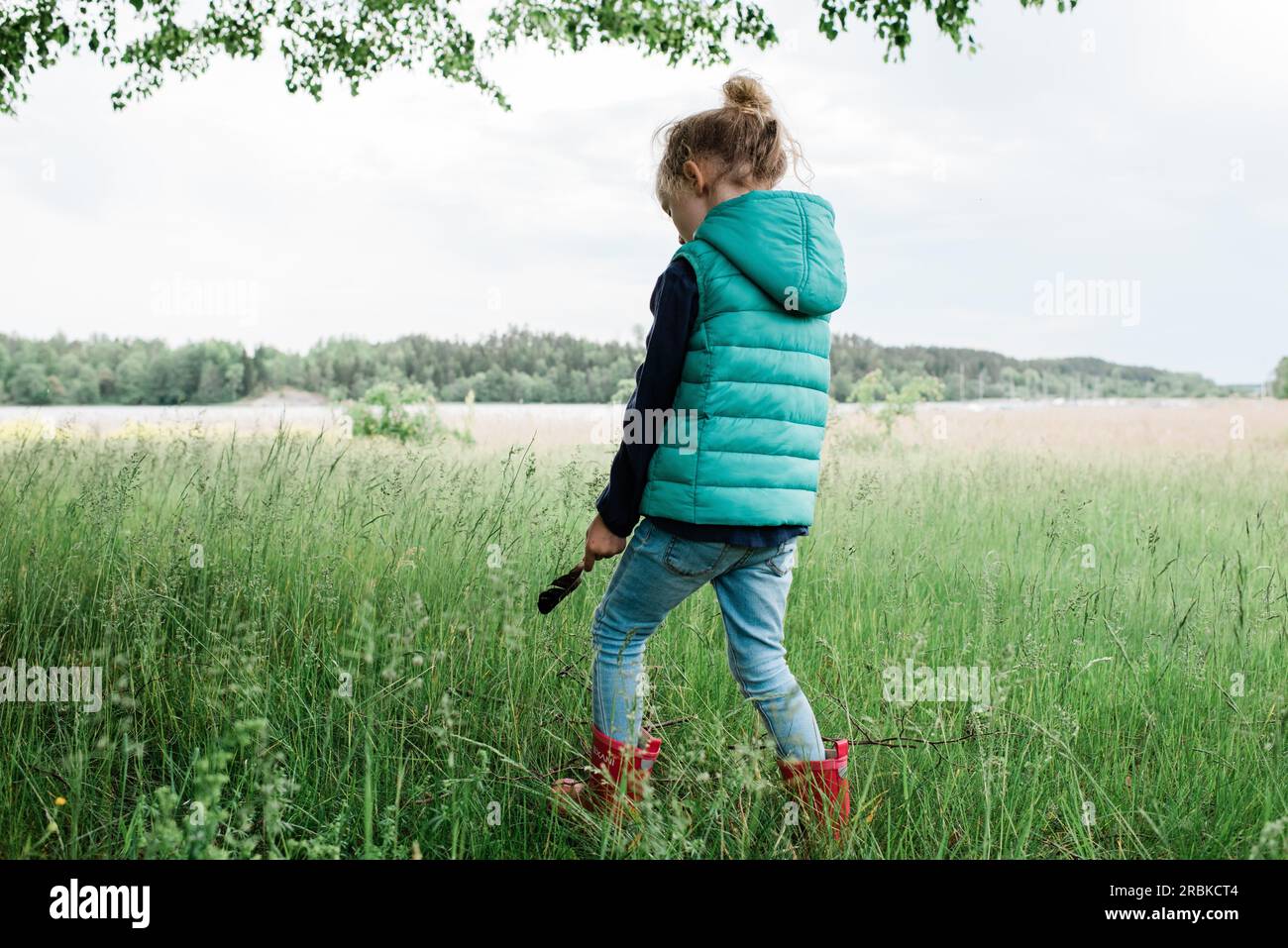 young girl walking through a field holding onto a feather Stock Photo ...