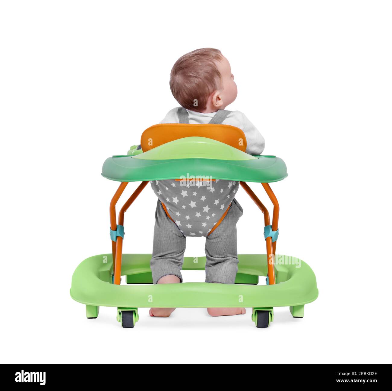 Cute little boy making first steps with baby walker on white background ...