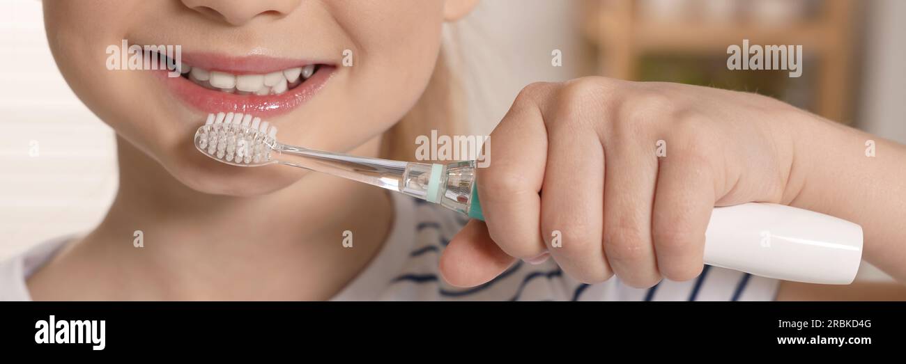 Little girl brushing her teeth with electric toothbrush in bathroom ...