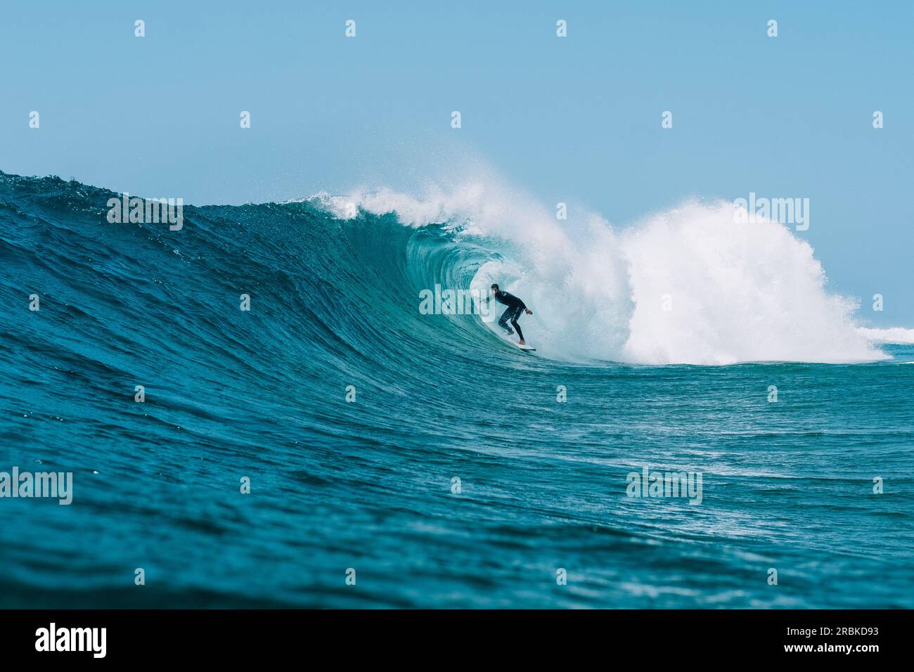 Pulled back view of a surfer in a barrel against a blue sky Stock Photo ...