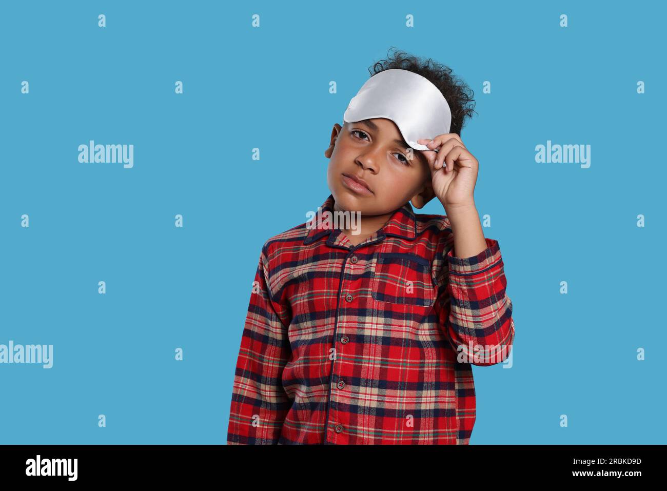 Boy with sleep mask on light blue background. Insomnia problem Stock ...