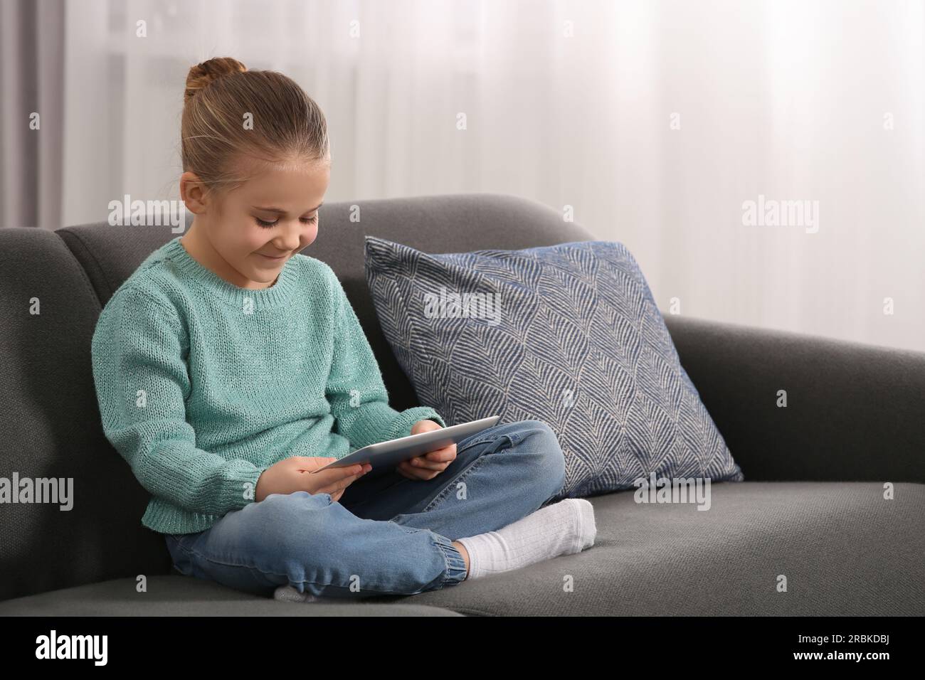 Little girl using tablet on sofa at home. Internet addiction Stock ...