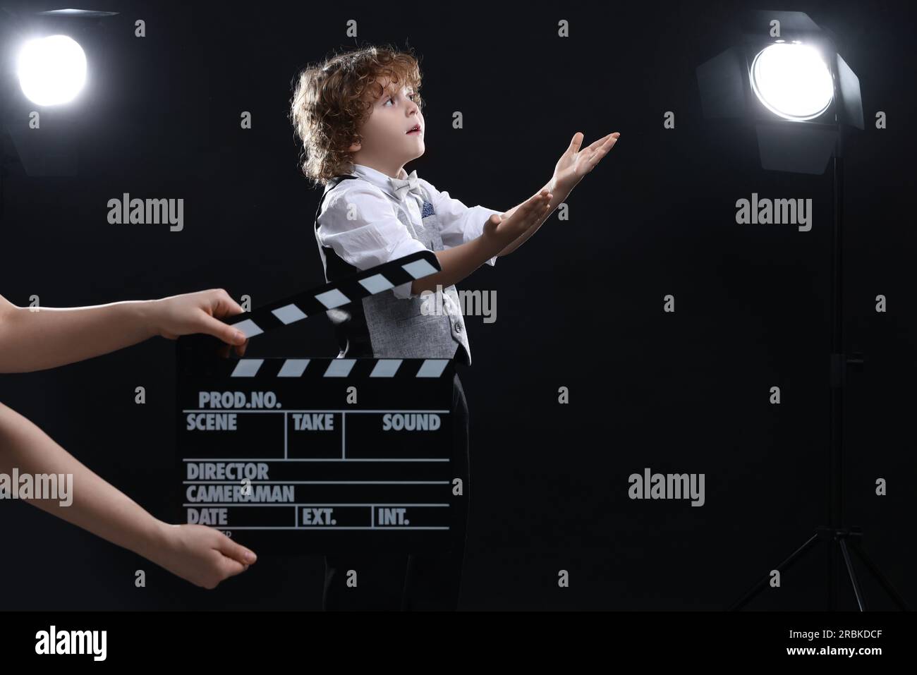 Cute boy performing while second assistant camera holding clapperboard ...
