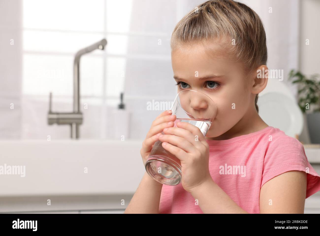 Cute little girl drinking fresh water from glass in kitchen Stock Photo - Alamy