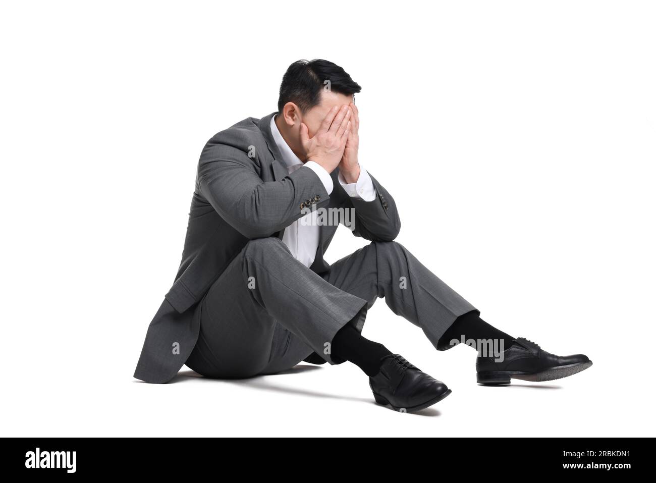 Tired businessman in suit sitting on white background Stock Photo - Alamy