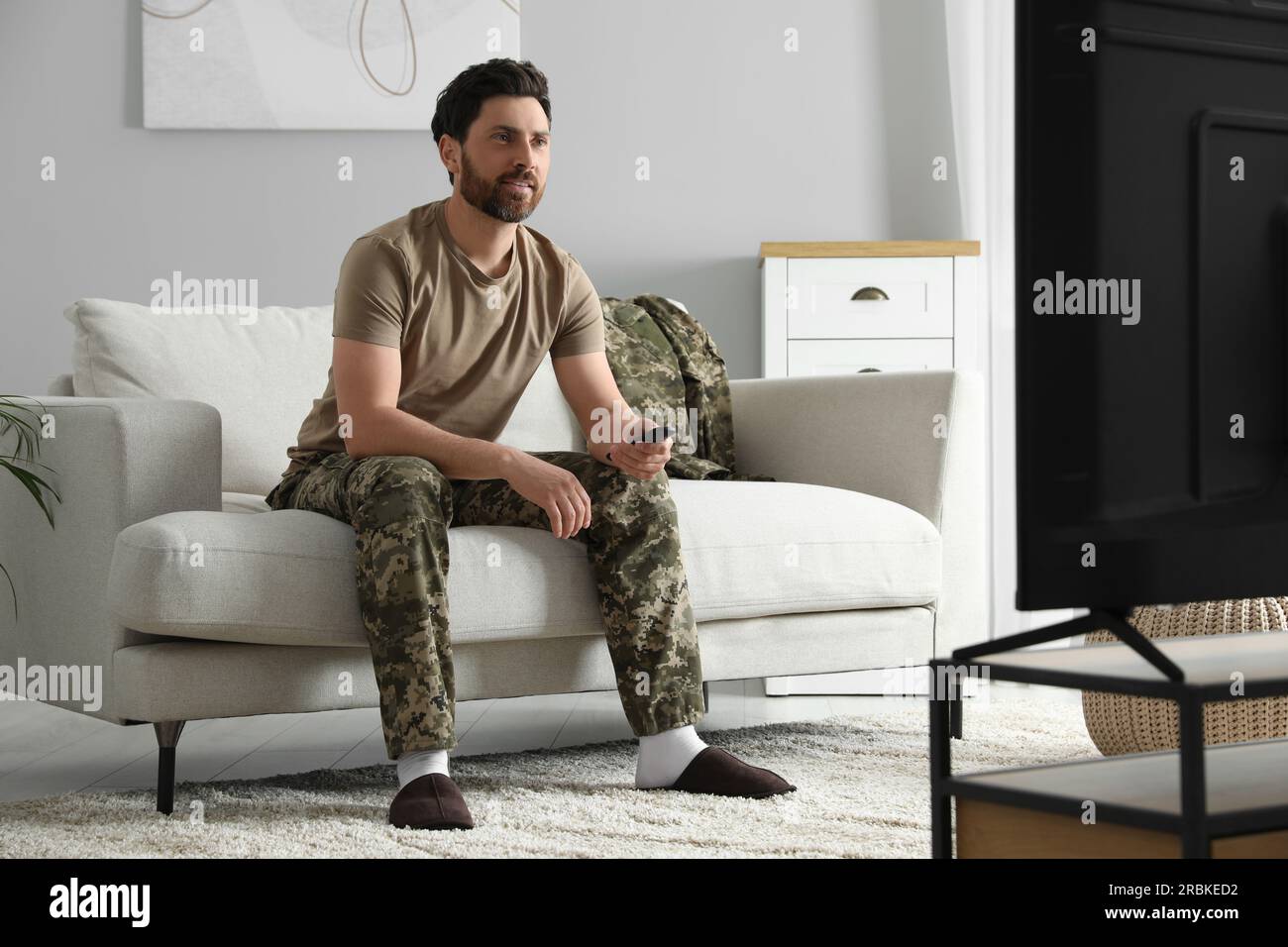 Soldier watching TV on sofa in living room. Military service Stock ...