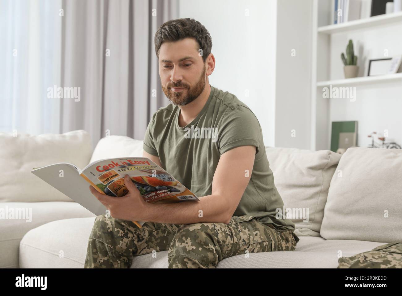 Soldier reading magazine on sofa in living room. Military service Stock ...