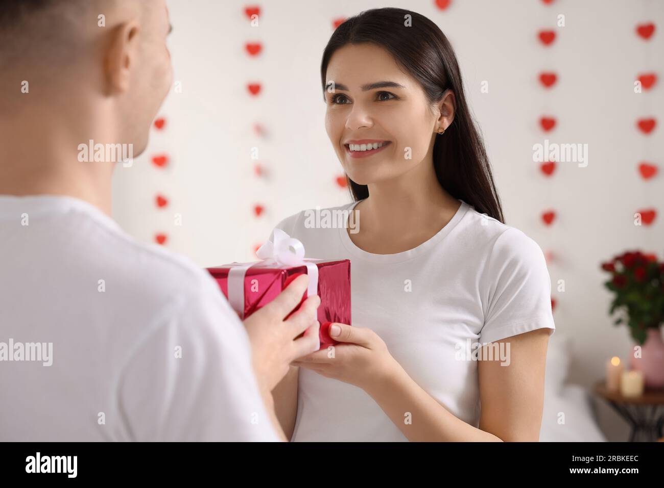 Young woman receiving gift from her boyfriend indoors. Valentine`s day ...