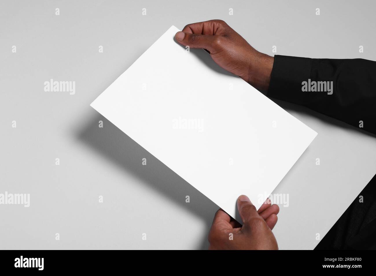 African American man holding sheet of paper on white background ...