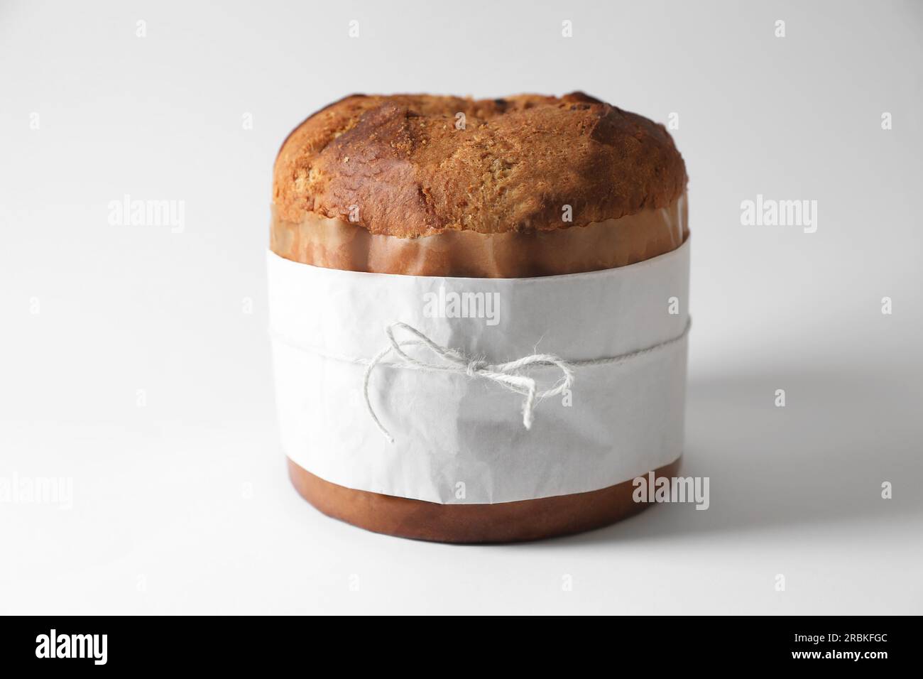 Delicious Panettone cake wrapped in parchment paper on white background ...