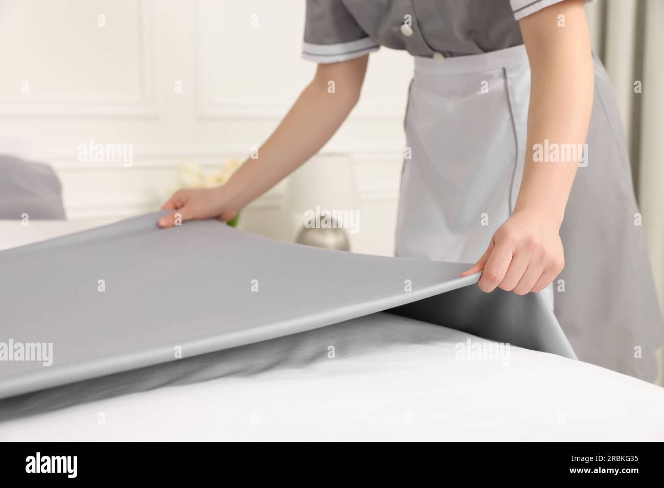 Maid making bed in hotel room, closeup Stock Photo - Alamy