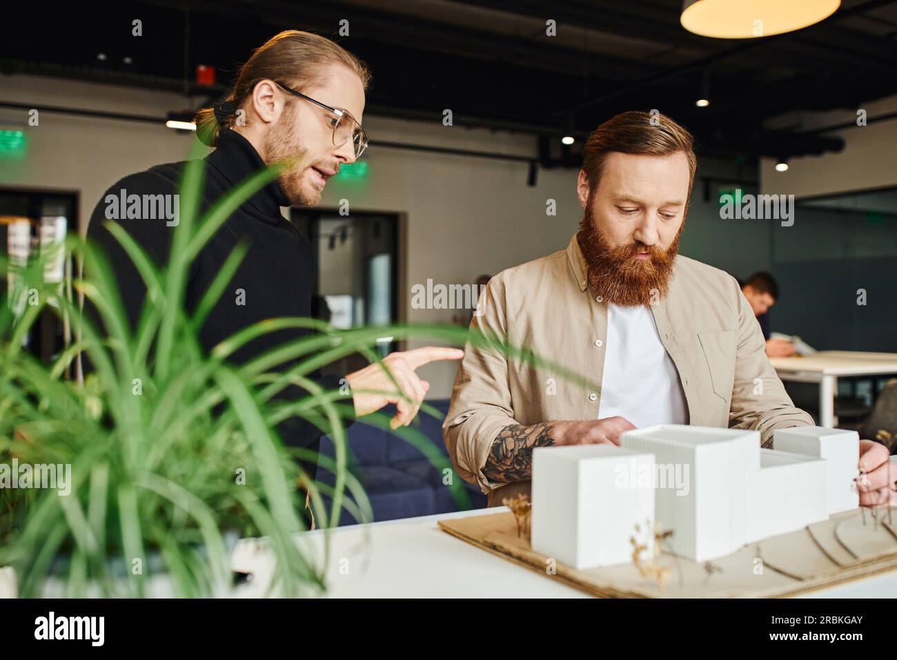 creative architect pointing at building model and discussing startup ...