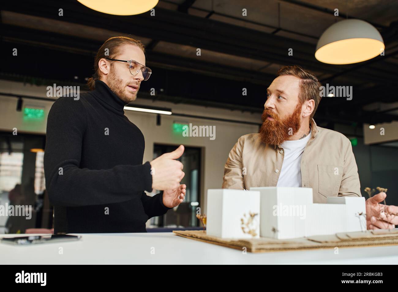 attentive and bearded architect listening to colleague in black ...