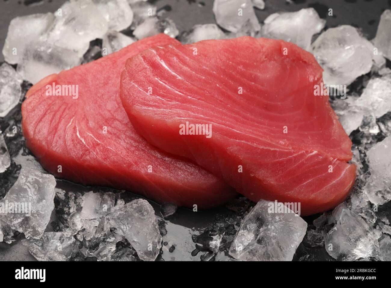 Raw tuna fillets and ice cubes on dark table Stock Photo - Alamy