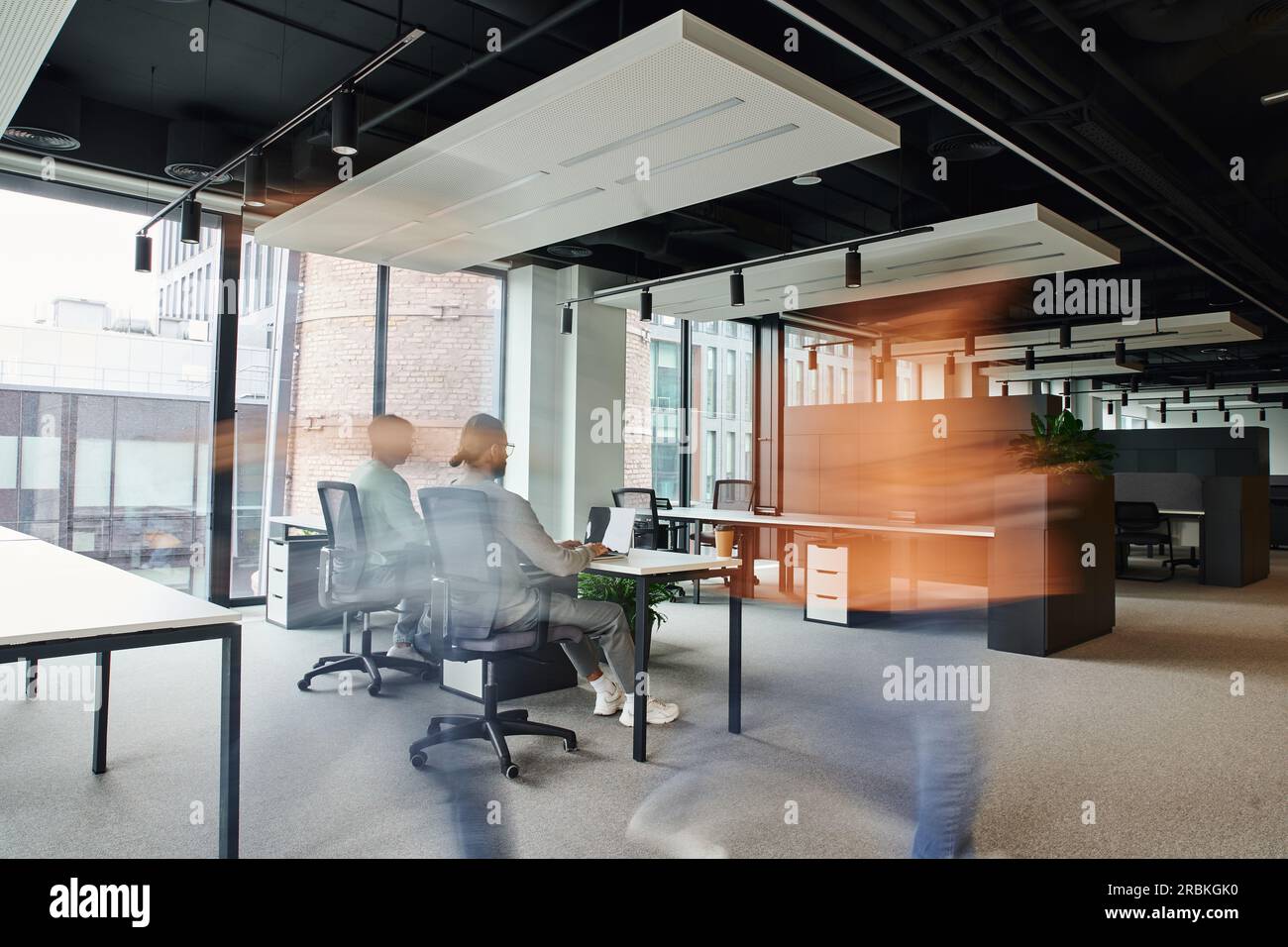 motion blur of man walking near business people working in open space ...