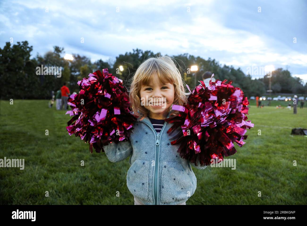 little girl smiling with pom poms outside at dusk Stock Photo - Alamy