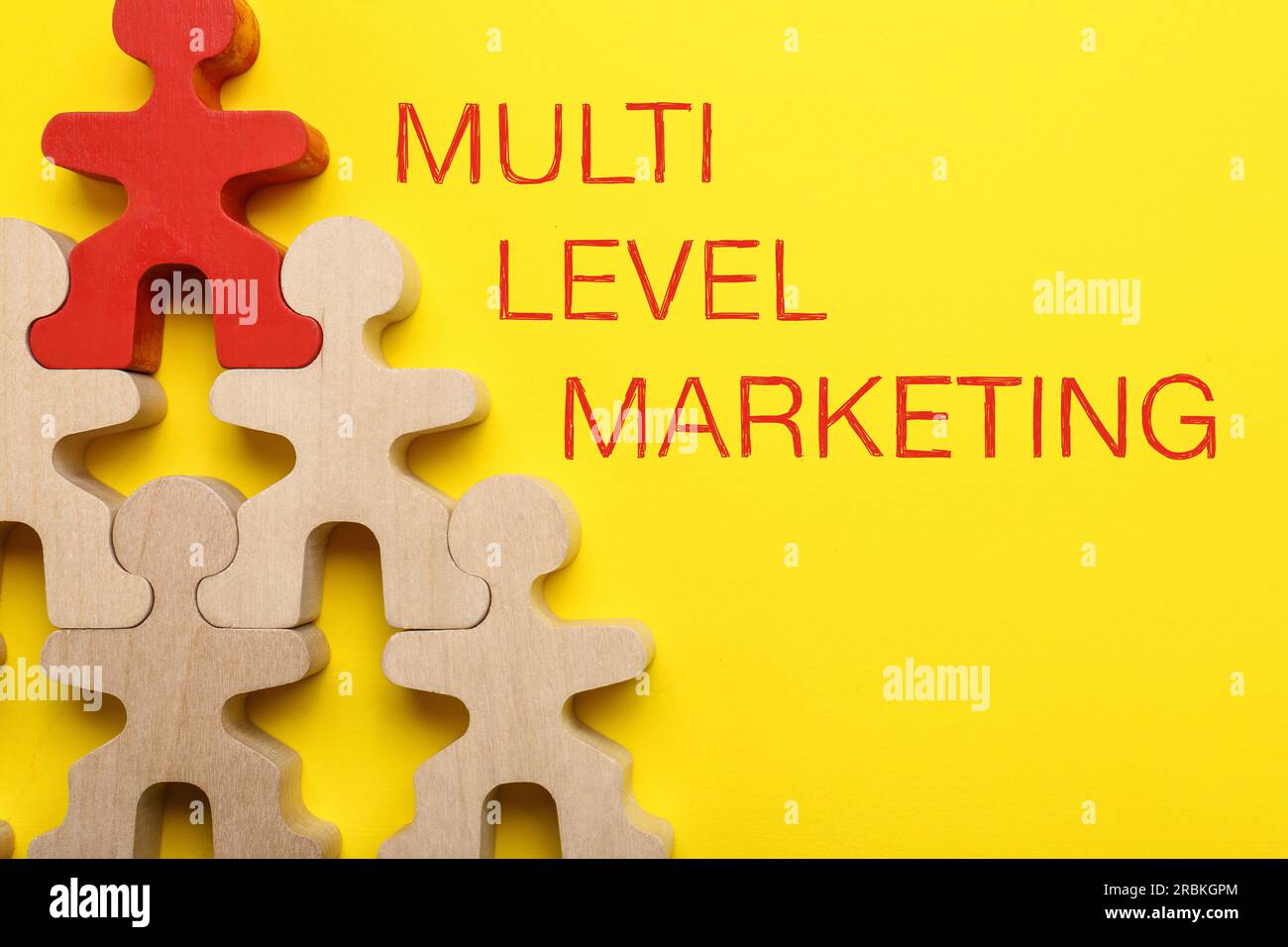 Multi-level marketing. Pyramid of wooden human figures with red one at ...