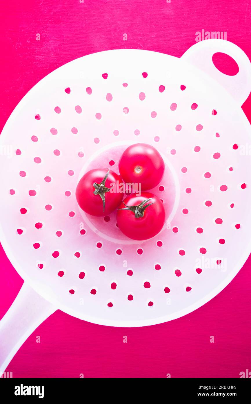 Top view of tomatoes in a strainer against red Stock Photo - Alamy