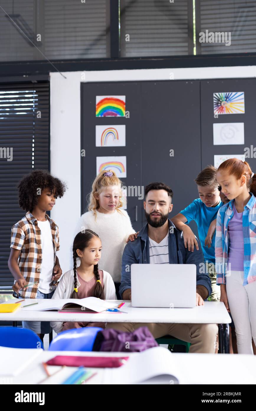 Vertical of diverse elementary schoolchildren and male teacher using ...