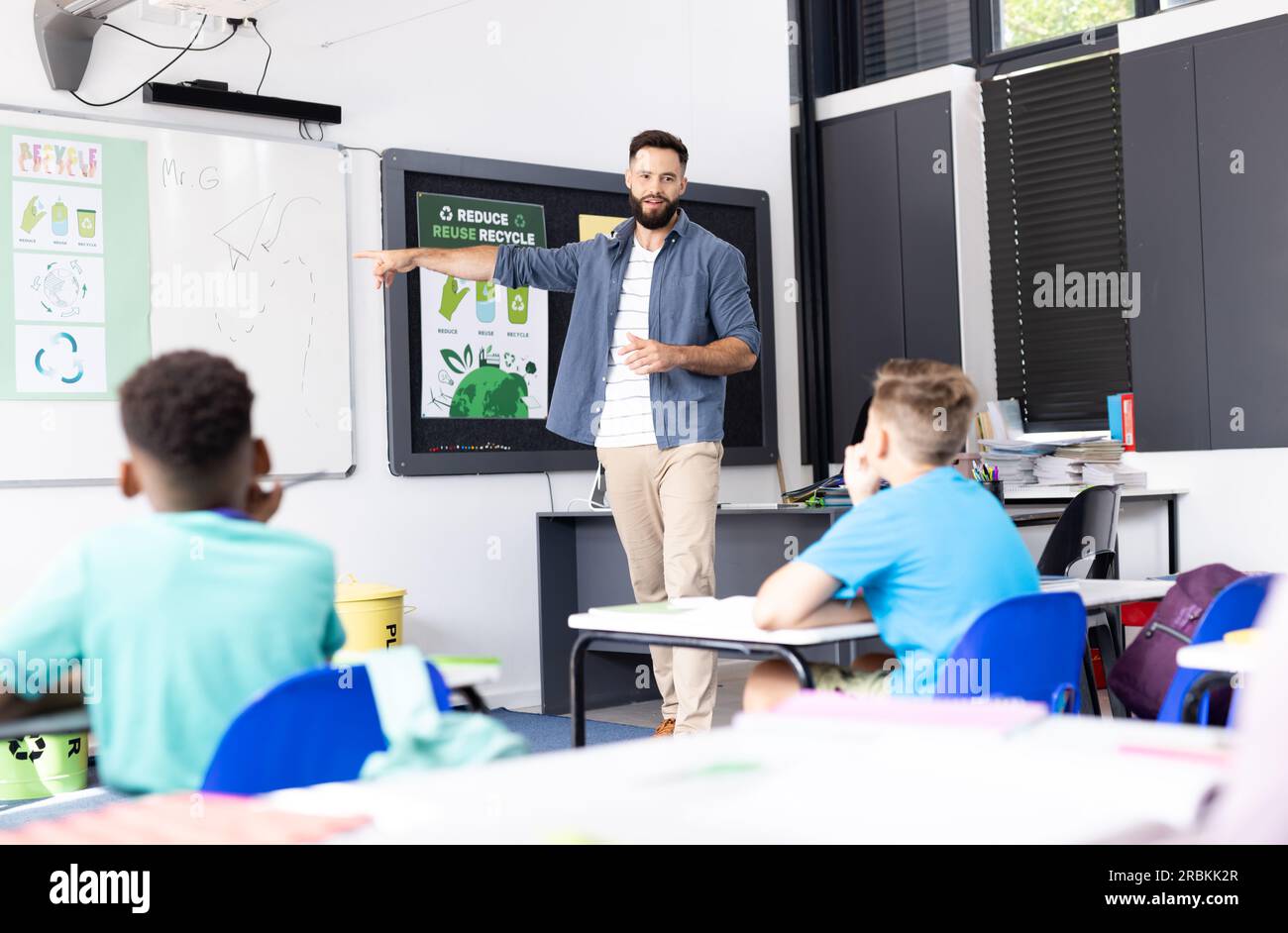 Caucasian male teacher using whiteboard in diverse elementary school ...