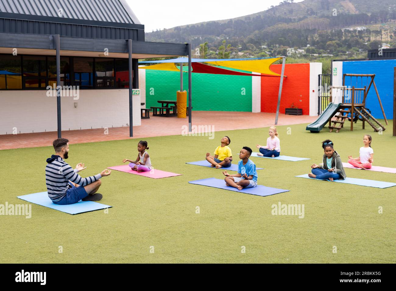 Diverse male teacher and elementary schoolchildren practicing ...