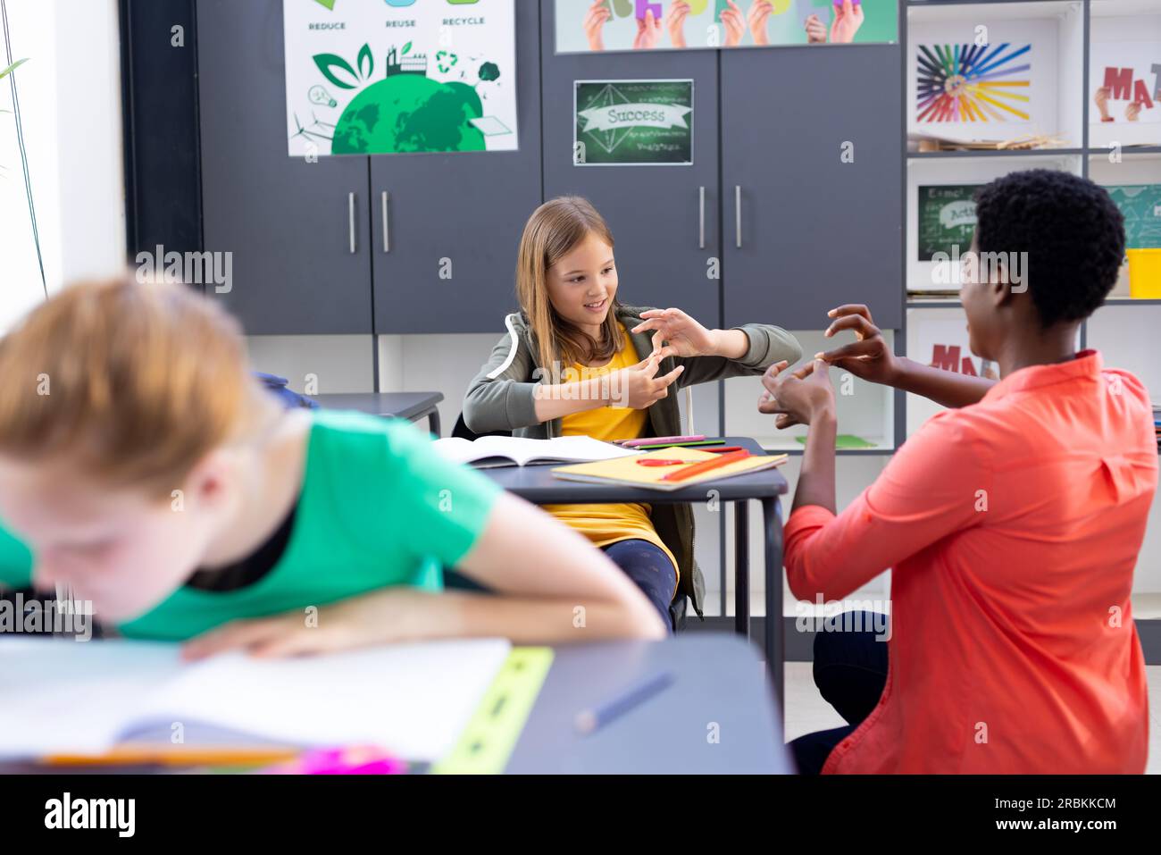 Diverse female school teacher and happy schoolgirl practicing sign ...